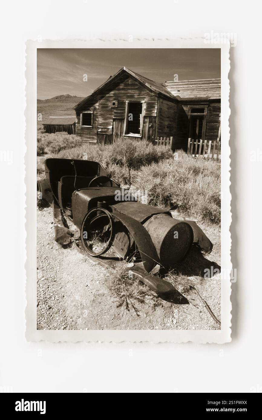 Individual parts of a rusting old car wreck in front of a wooden house ...