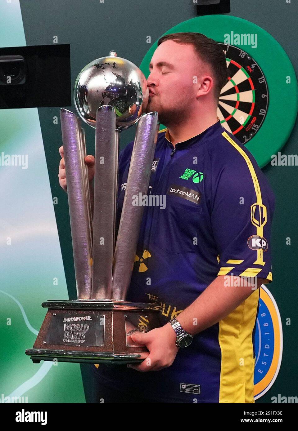 Luke Littler of England kisses the trophy after winning the final ...