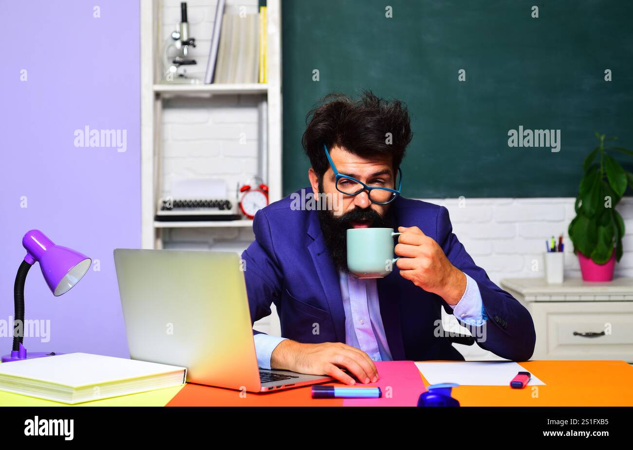 Tired male teacher drinking coffee during break. Fatigued school ...