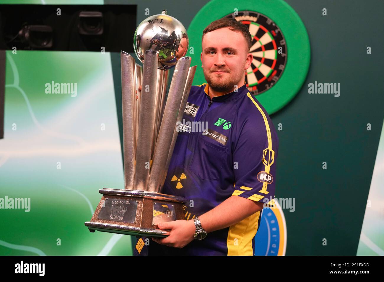 Luke Littler of England holds the trophy after winning the final ...