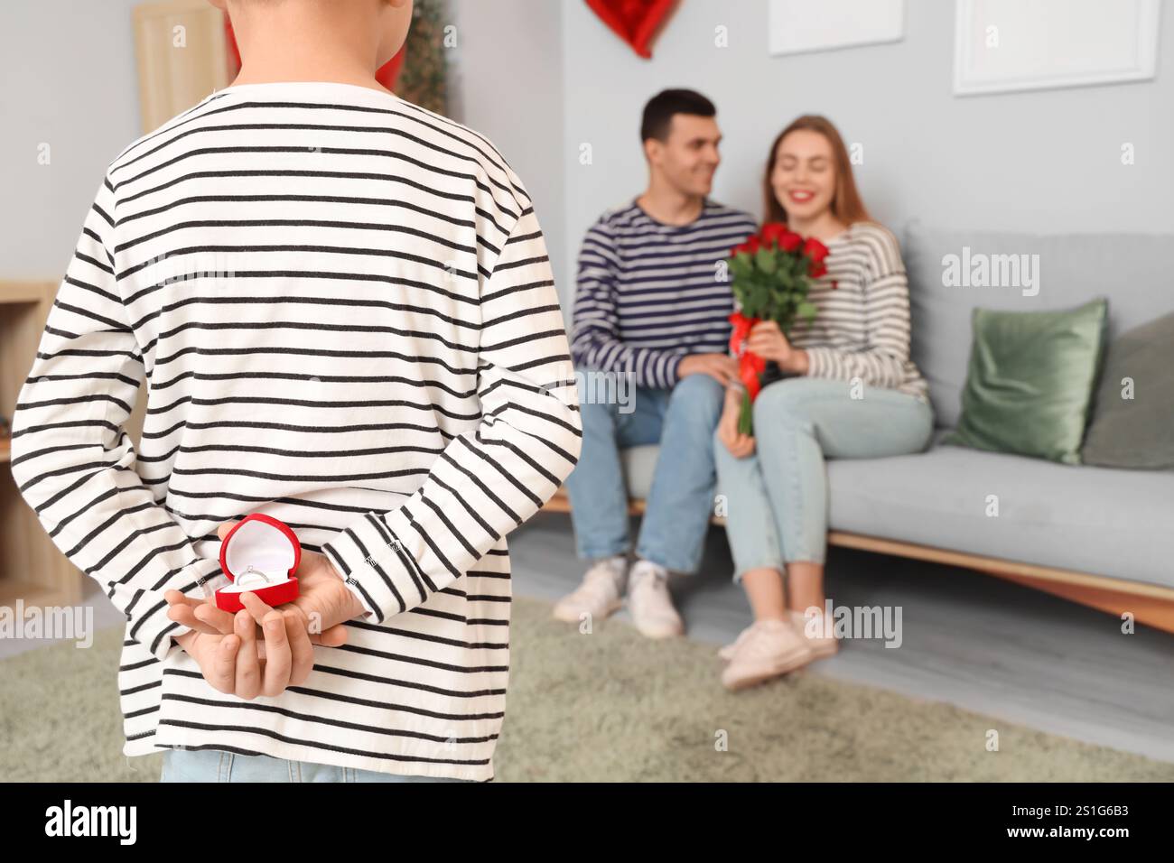 Little boy hiding ring behind his back from parents at home on ...