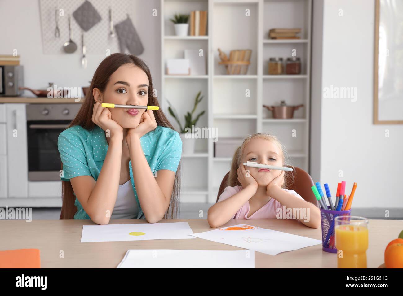 Nanny and funny little girl with pens drawing in kitchen Stock Photo ...
