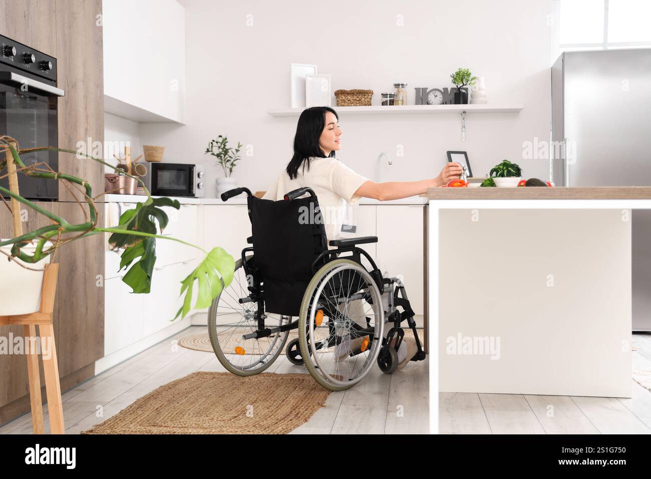 Beautiful young woman in wheelchair cooking at home Stock Photo - Alamy