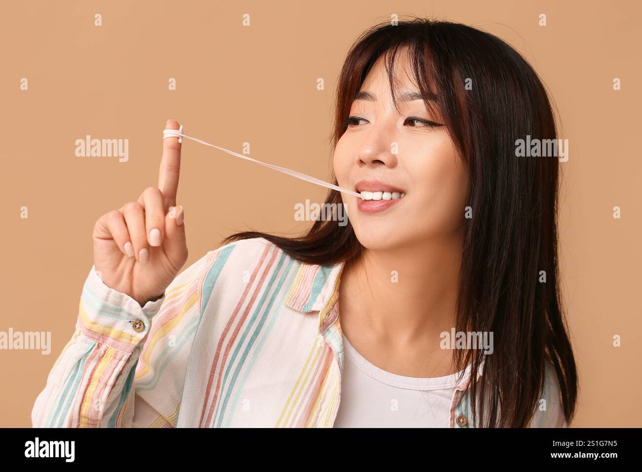 Pretty young Asian woman pulling chewing gum on beige background Stock ...