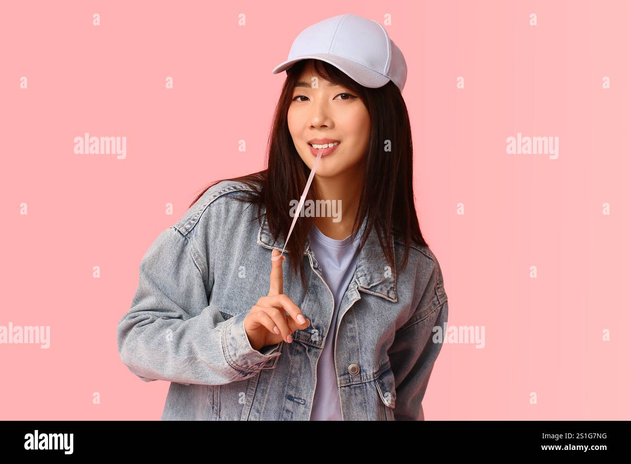 Pretty young Asian woman pulling chewing gum on pink background Stock ...