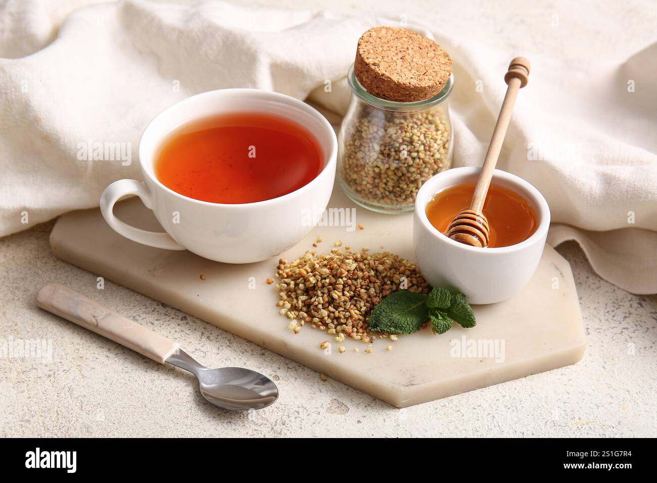 Cup of hot buckwheat tea with mint and bowl of honey on white ...