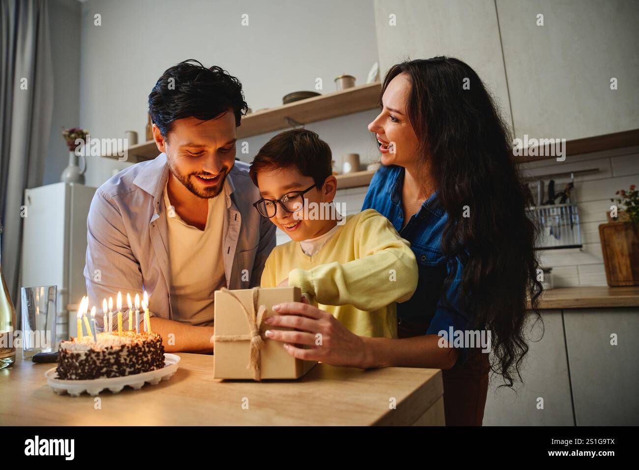 Celebrating a birthday with family at home while opening a gift in the ...