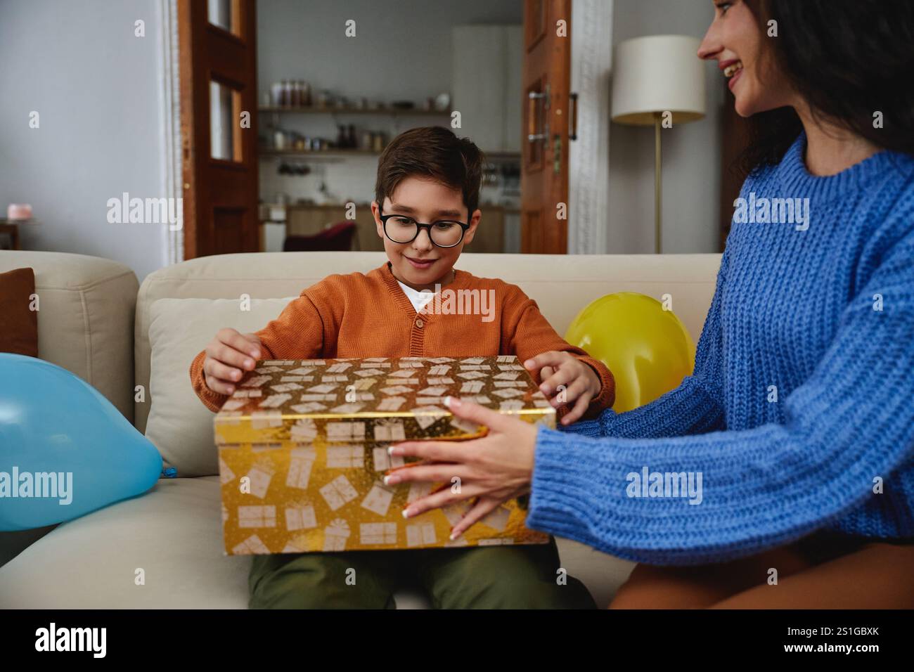 Child opens a beautifully wrapped gift with joy at home during a ...
