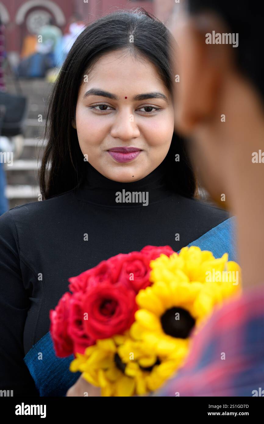 Indian young woman receiving a colourful bouquet of sunflowers and ...