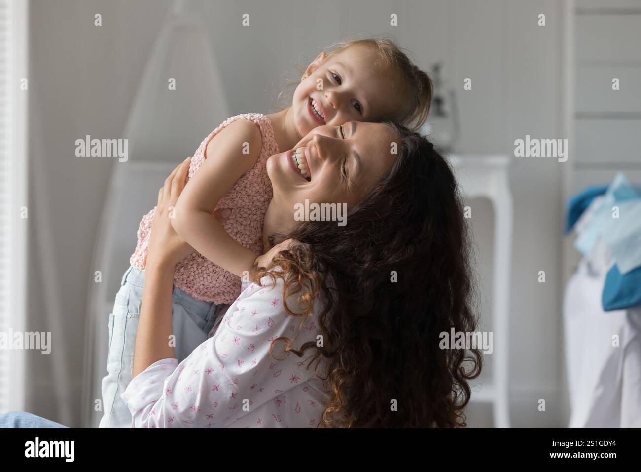 Happy millennial mother cuddle hold in embraces beloved little daughter ...