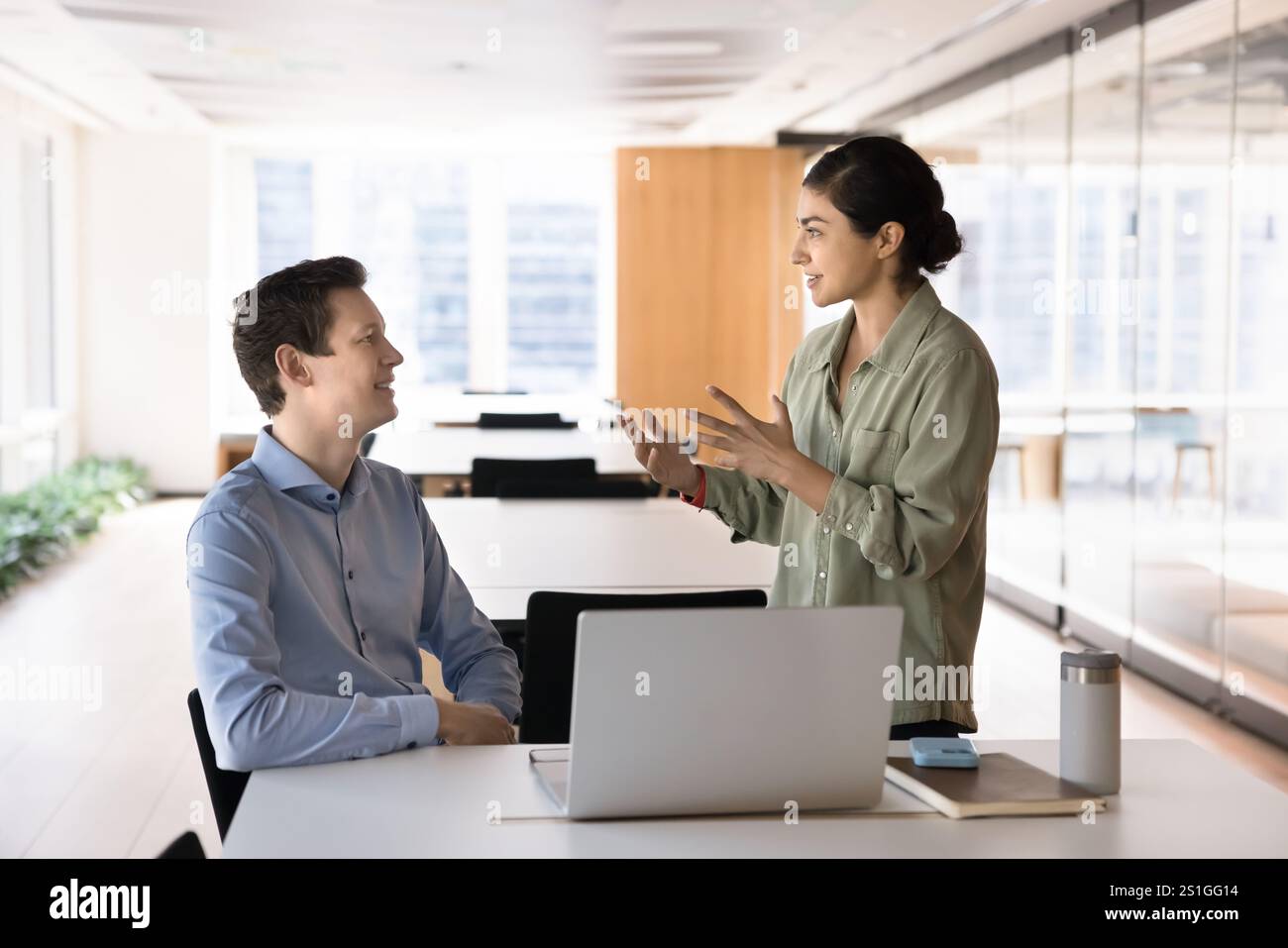 Positive diverse couple of colleagues talking at workplace Stock Photo ...