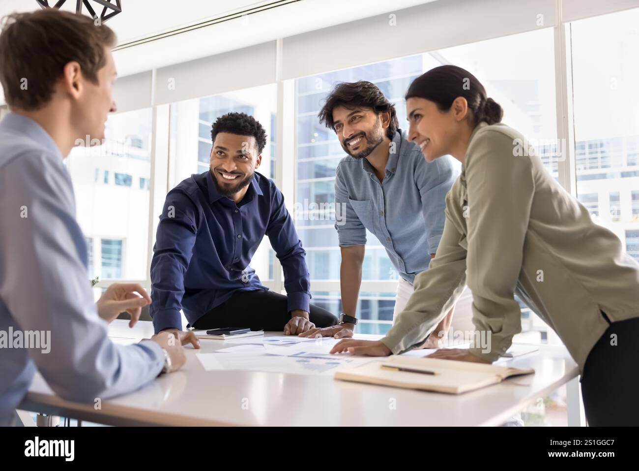 Multiethnic business team of young colleagues listening to male leader ...