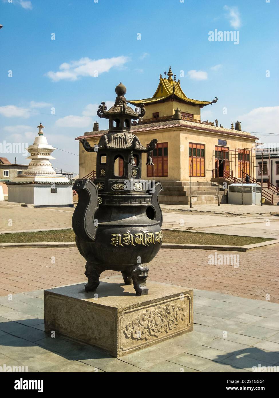 A black and gold Chinese vase sits on a pedestal in front of a building ...