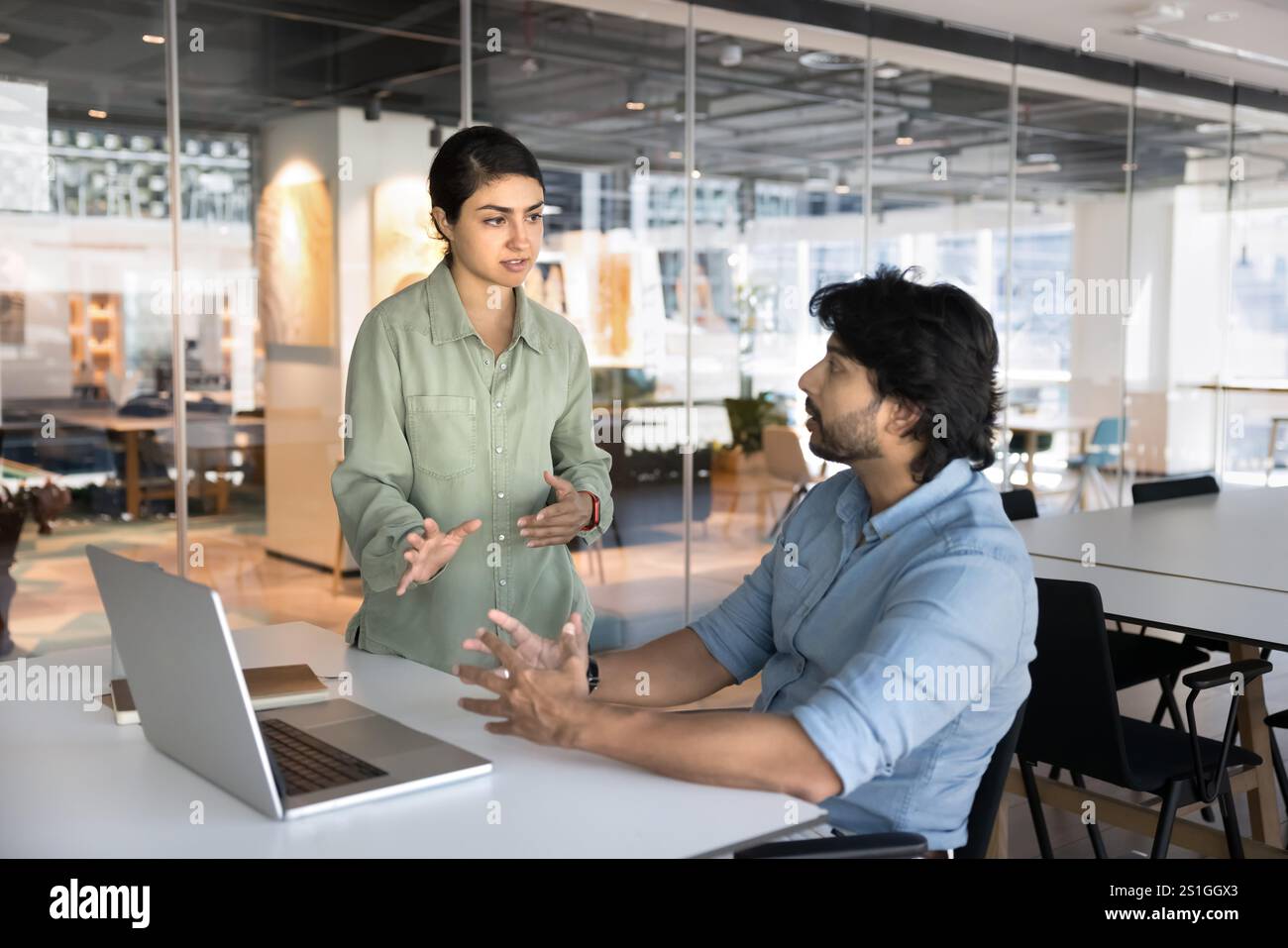 Two serious busy young Indian professionals talking at workplace Stock ...