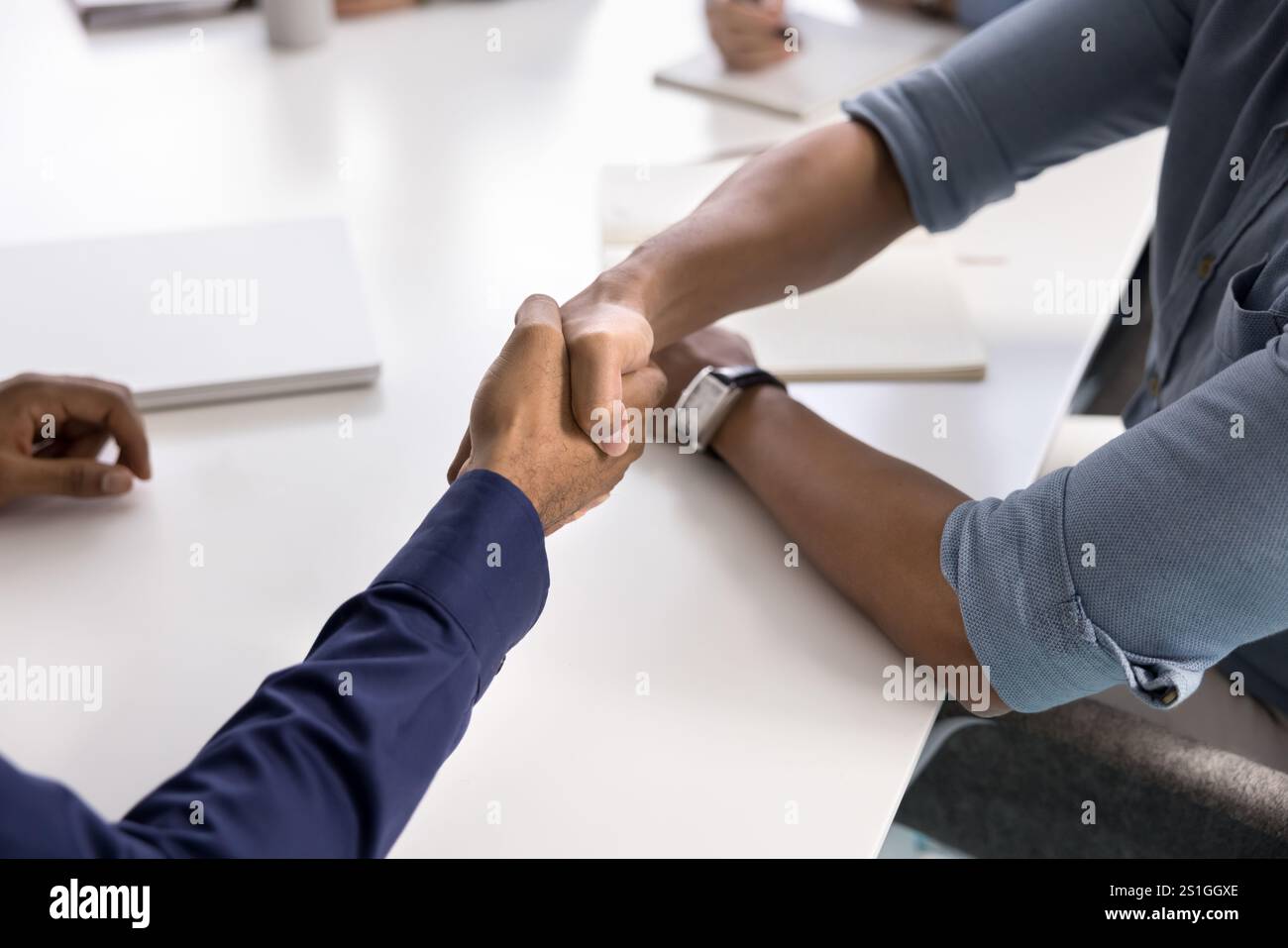 Two young diverse businessmen shaking hands over meeting table Stock ...