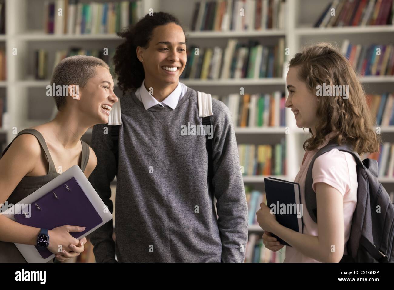 Laughing multiethnic students talk with familiar teenage girl at ...