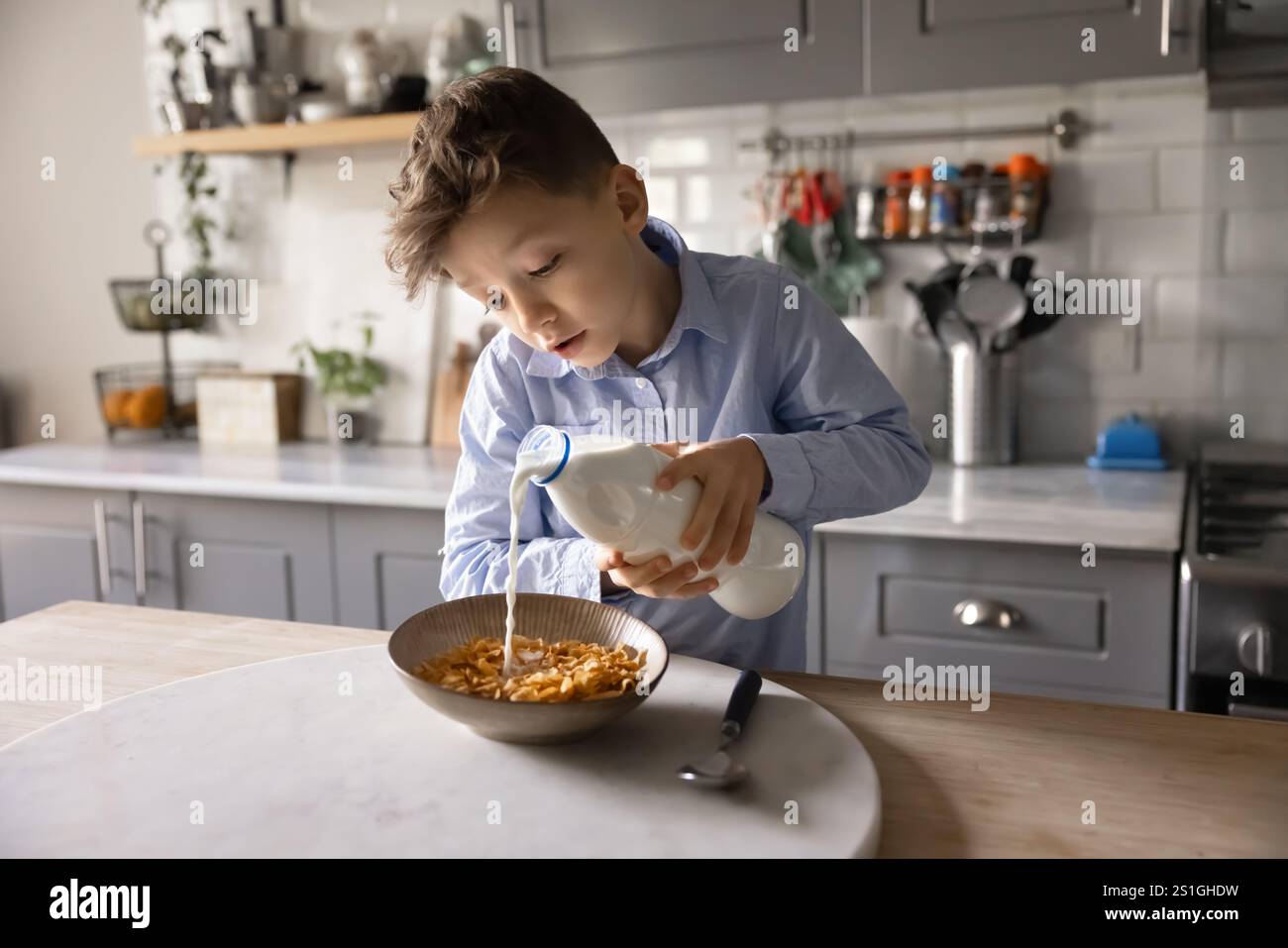 Cute kid pouring milk from bottle into bowl with flakes Stock Photo - Alamy