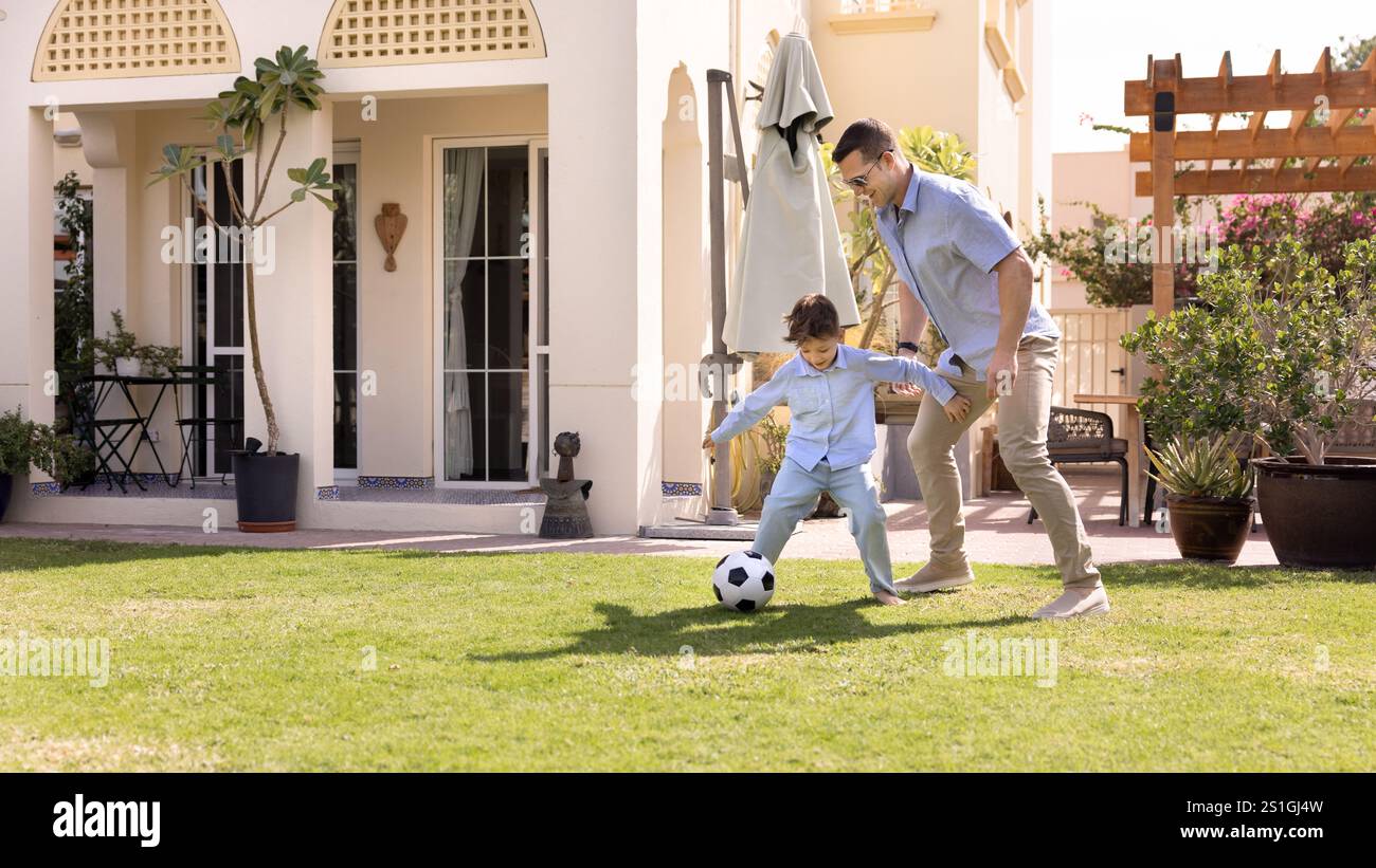 Active dad and sporty son boy playing soccer on backyard Stock Photo ...