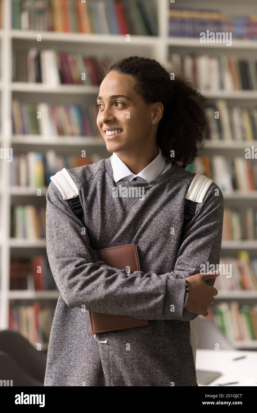 Young ethnic man student stand in library in dreamy pose Stock Photo ...