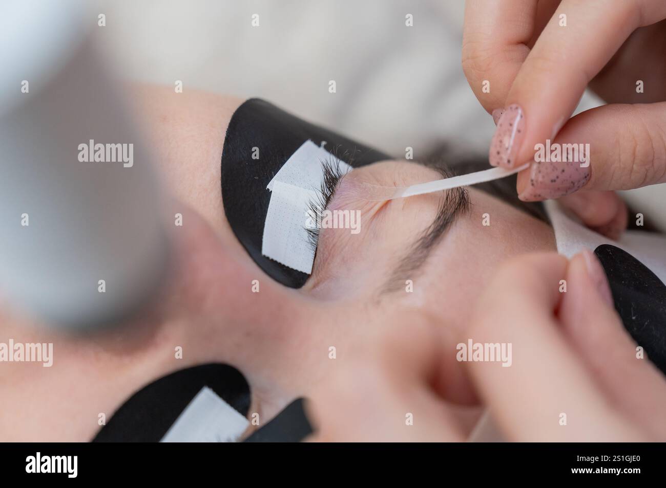 A specialist glues a client's drooping eyelid before eyelash extensions ...