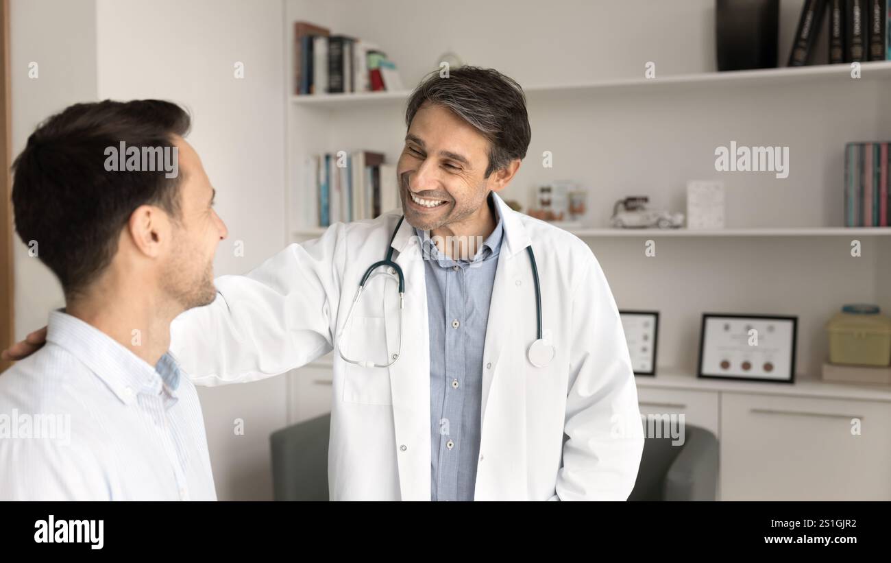 Positive successful male Latin doctor man touching patients shoulder ...