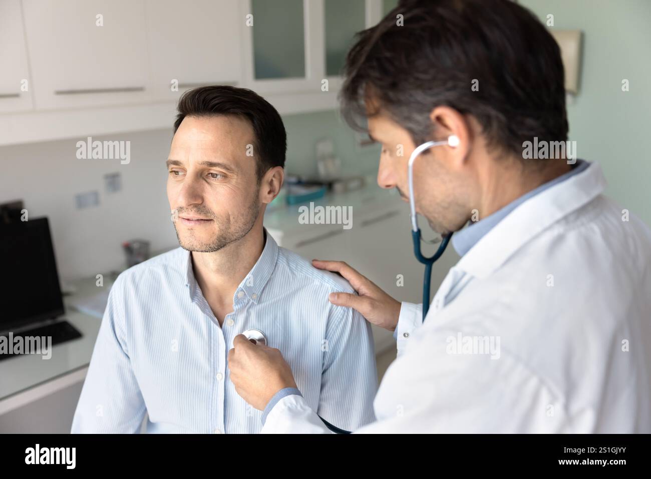 Serious clinic cardiologist doctor examining man, applying stethoscope ...