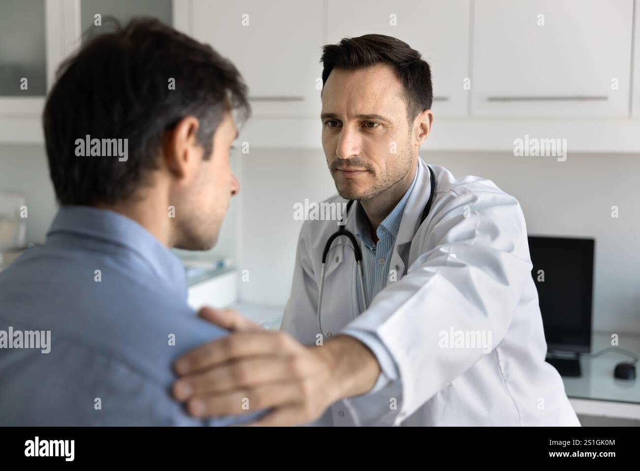 Serious caring doctor touching patients shoulder with sympathy Stock ...