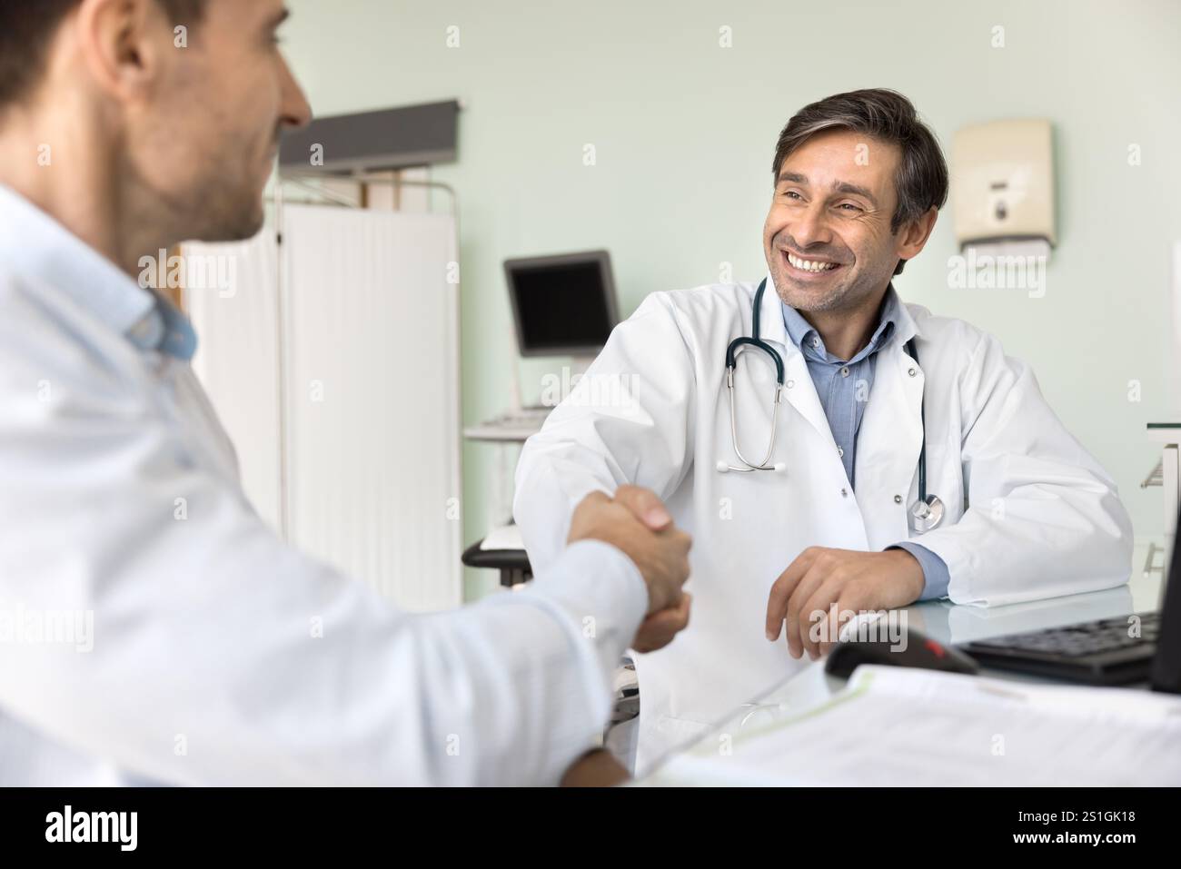 Positive successful Latin doctor giving handshake to patient Stock ...