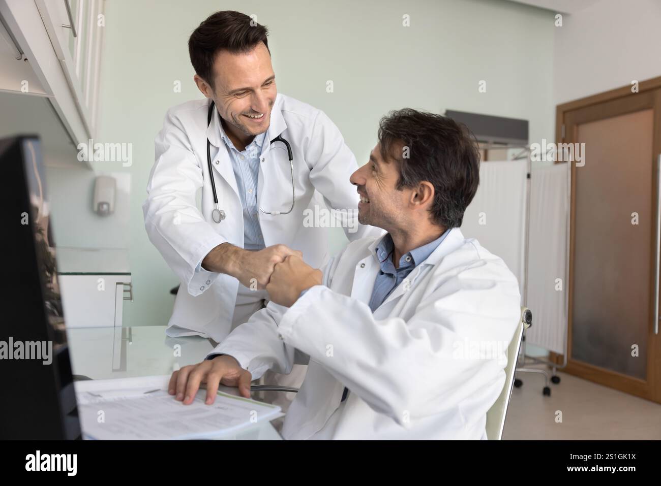 Two happy male doctors giving high five in clinic office Stock Photo ...