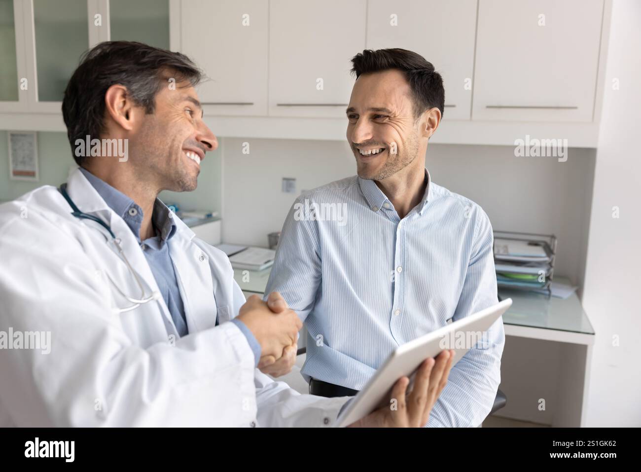 Cheerful Latin patient giving handshake to doctor with gratitude Stock ...