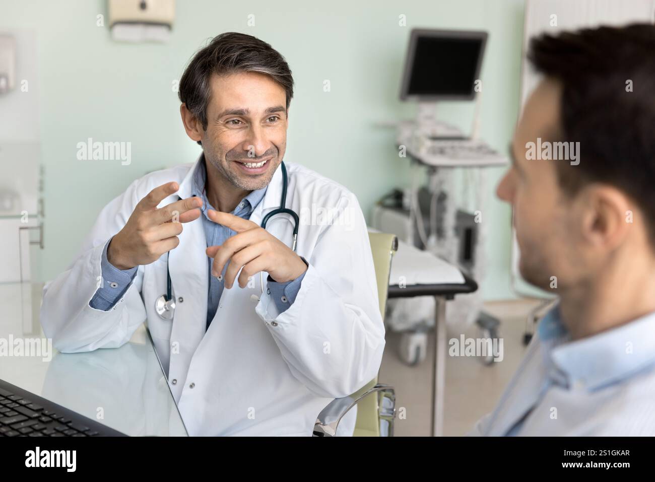 Positive Latin doctor man talking to male patient at workplace Stock ...