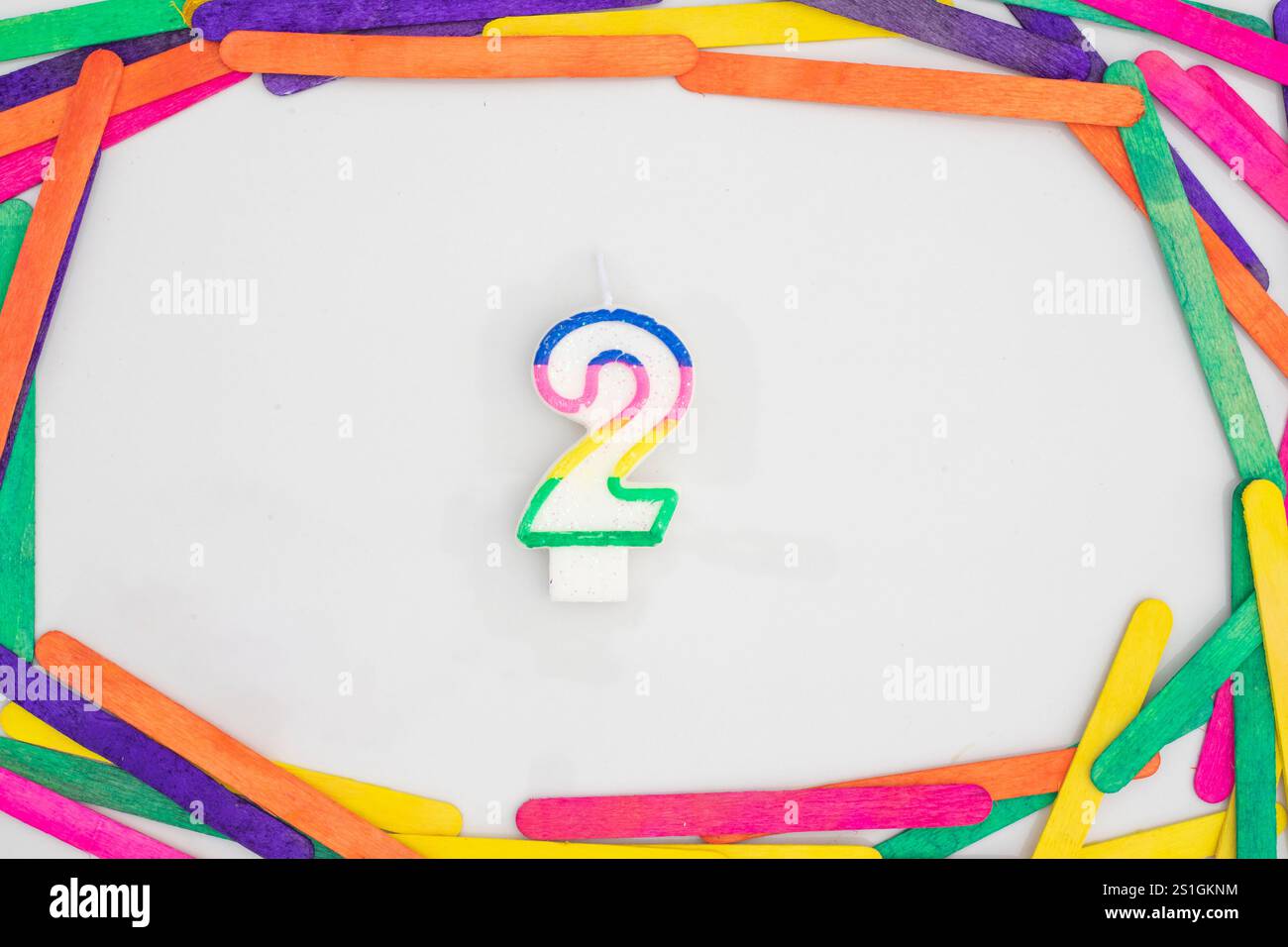 Number 2 shape candle with colorful popsicle sticks on white isolated ...