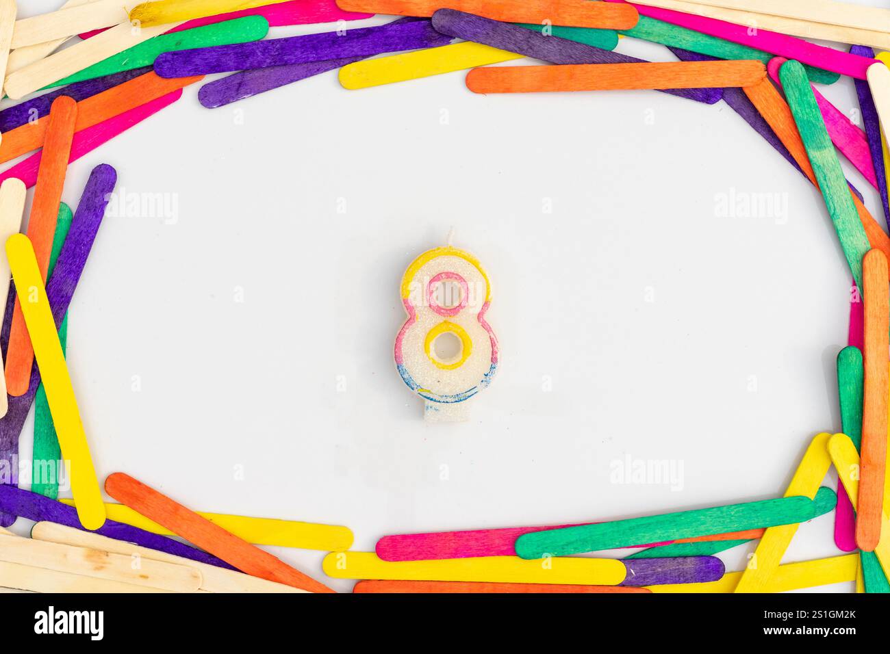 Colorful number eight candle with popsicle sticks frame on white ...