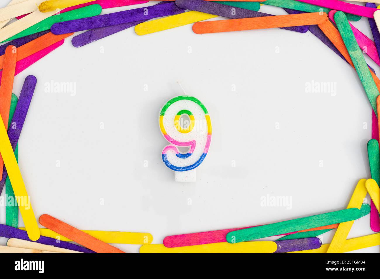 Vibrant number nine candle with popsicle stick border on white ...