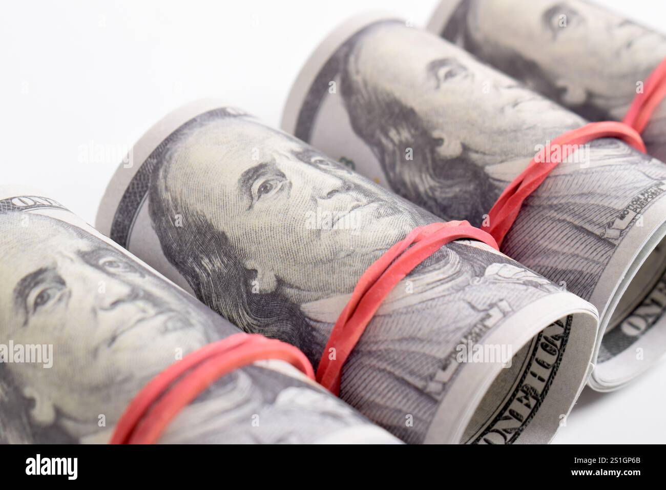 A row of rolled hundred dollar bills with rubber bands isolated on ...