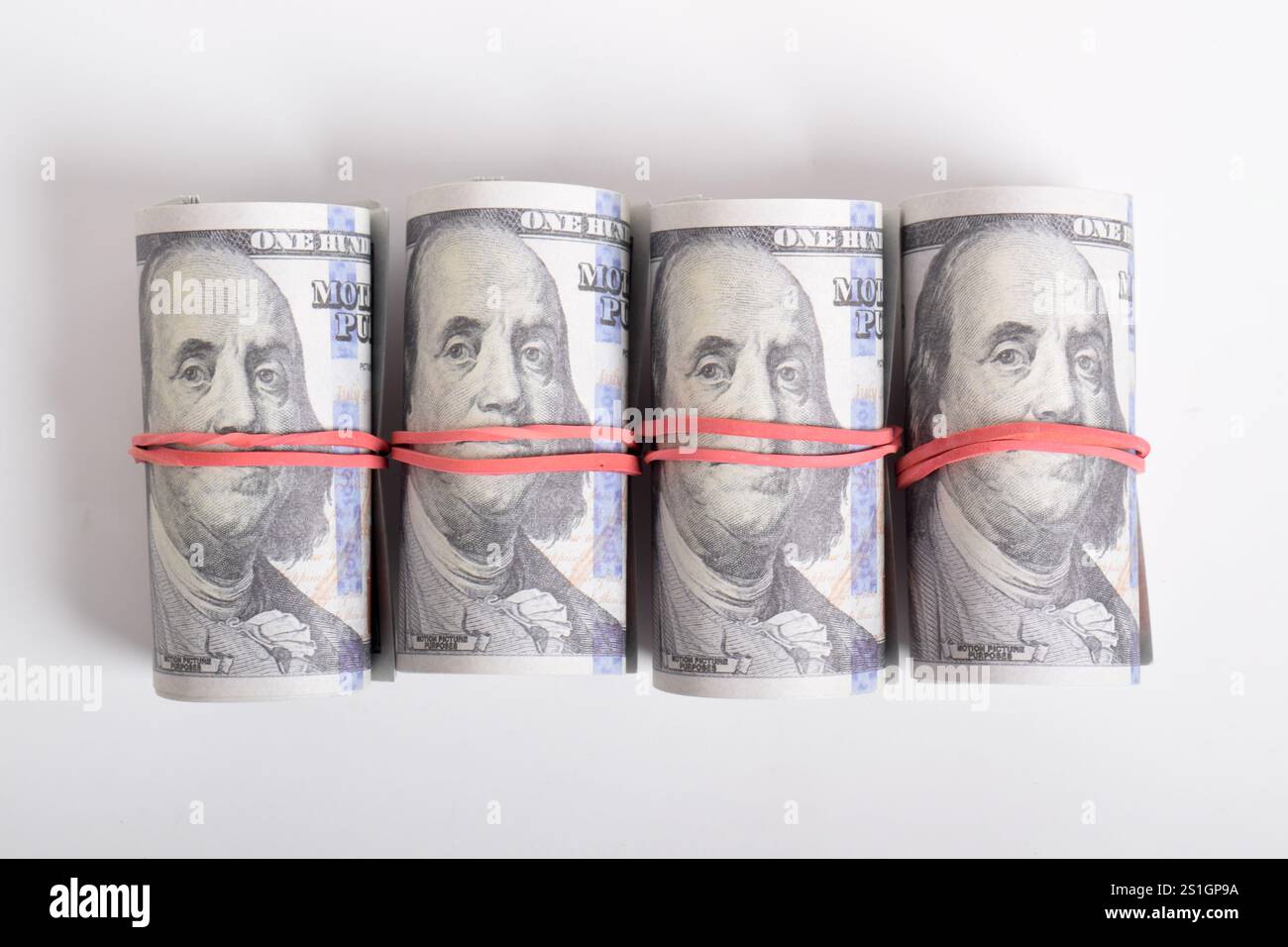 A row of rolled hundred dollar bills with rubber bands isolated on ...