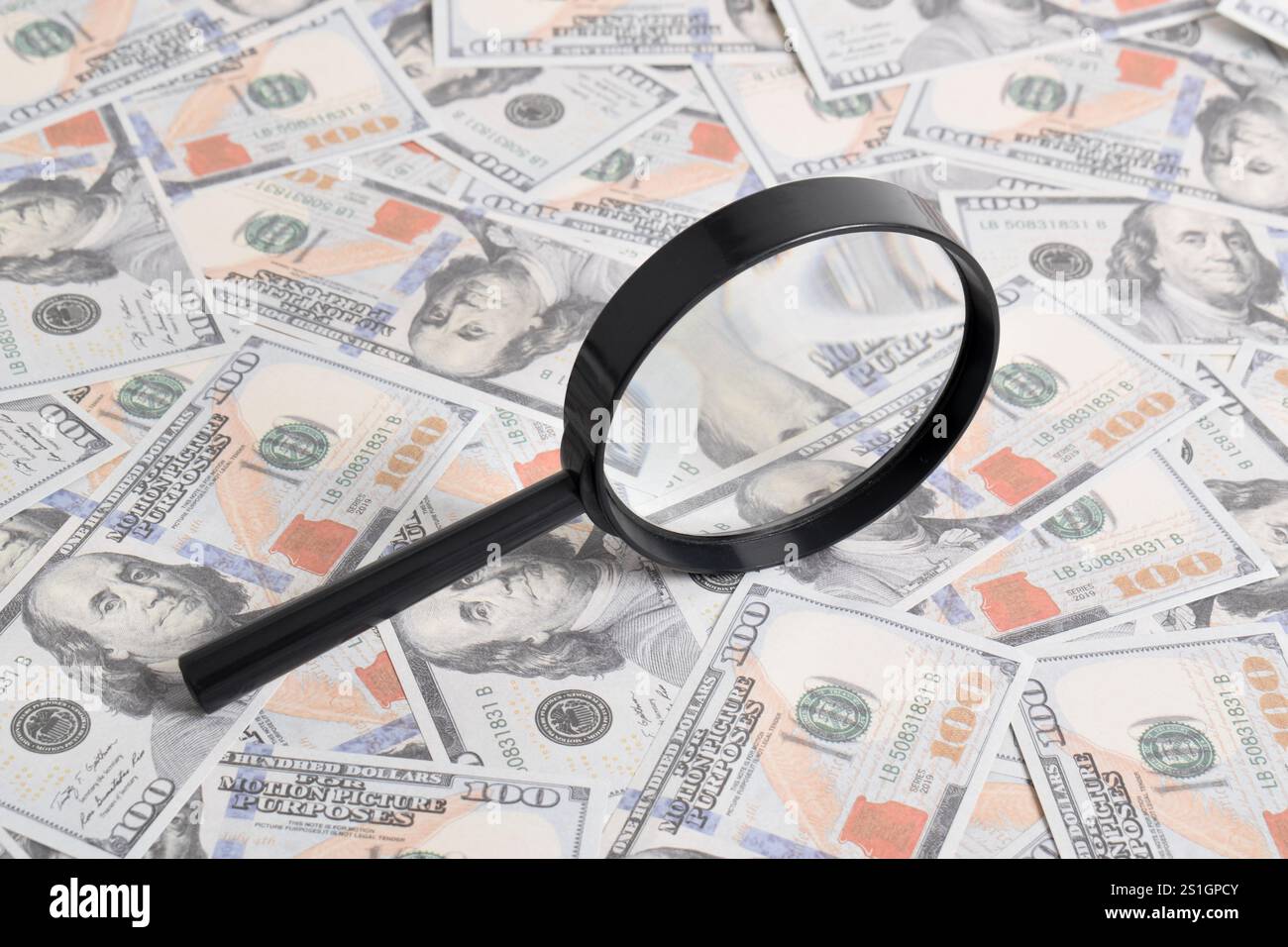 Magnifying glass on the background of a bundle of dollars on the table ...