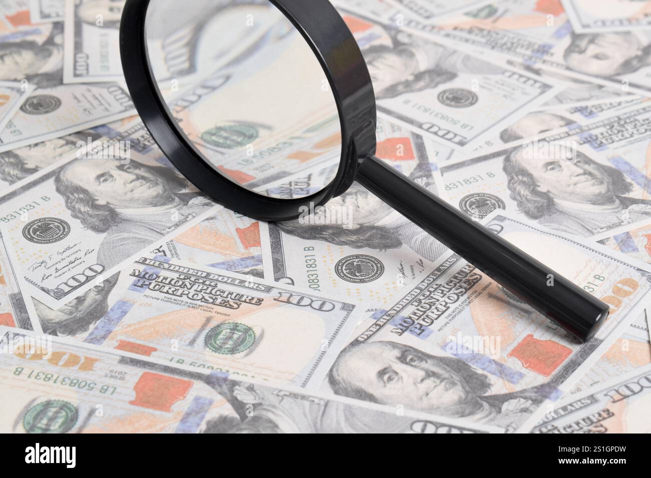 Magnifying glass on the background of a bundle of dollars on the table ...