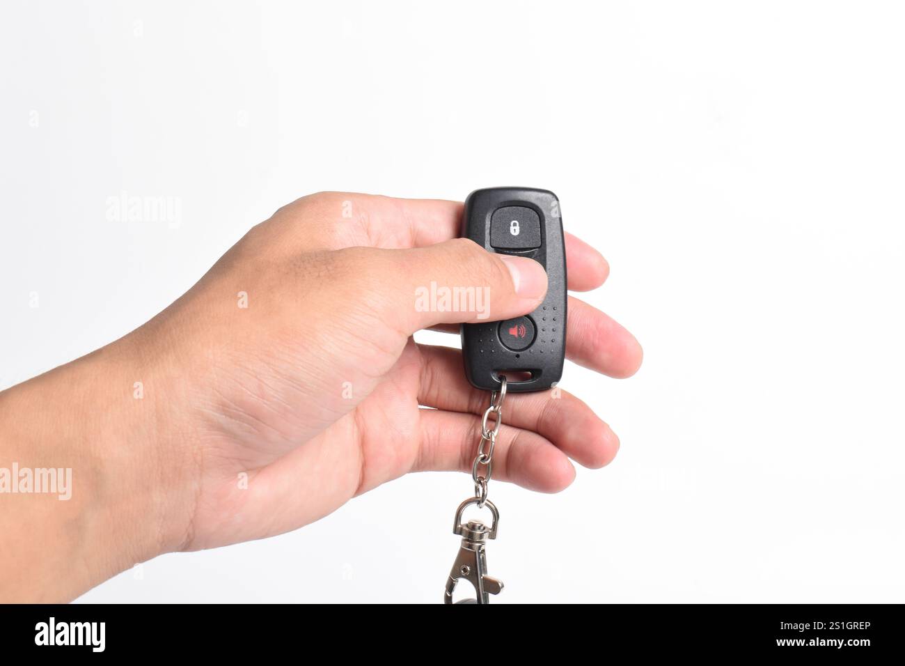 A man's hand holds a car key with remote control isolated on a white ...