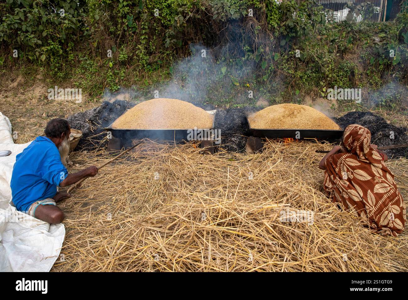 A man and woman boil paddy in the Haor region of Mohonganj, Netrokona ...