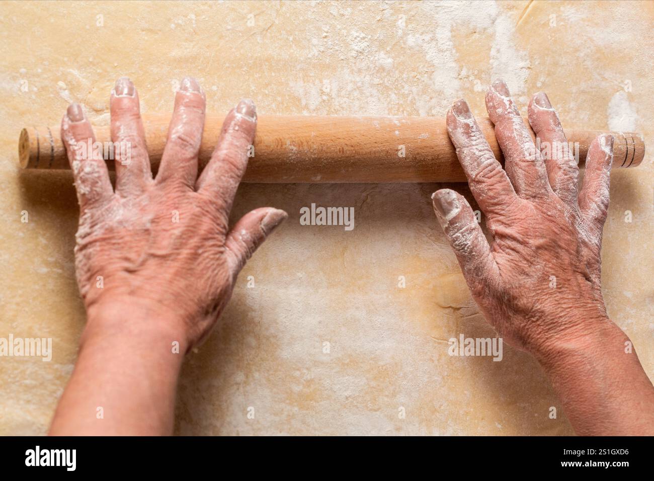 Closeup of man rolling dough with rolling pin, cooking process top view ...