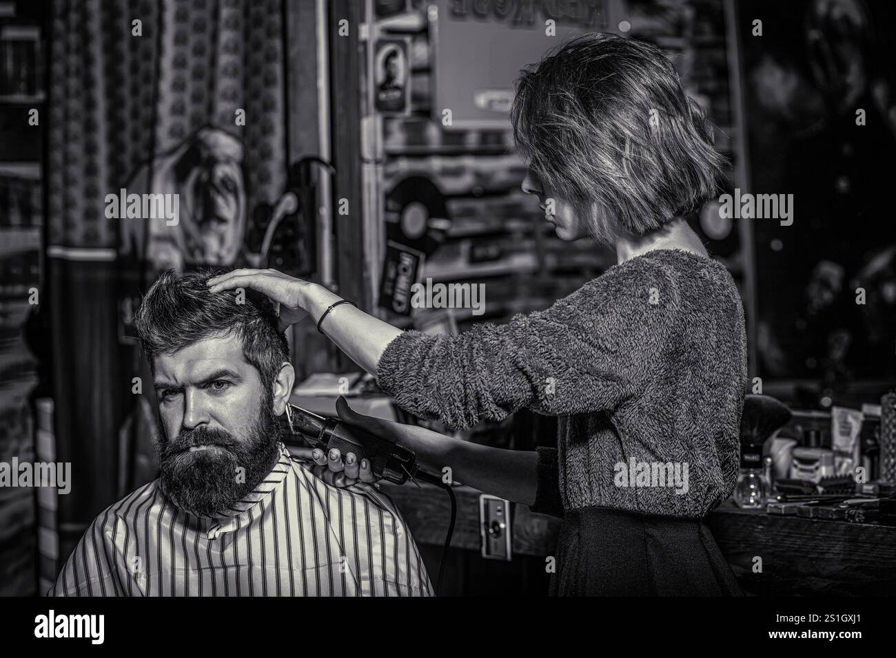 Client during beard shaving in barbershop. Female barber at salon ...