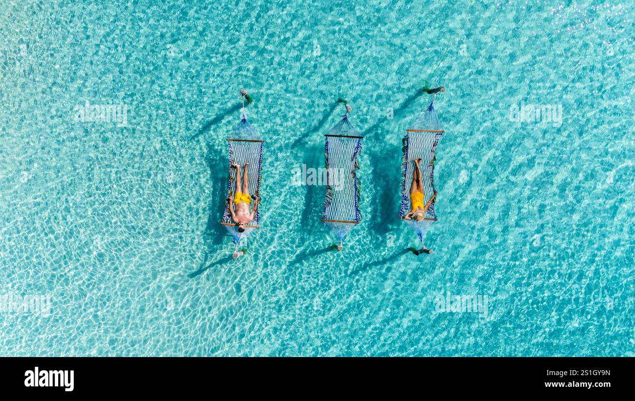 hammocks gently sway above mesmerizing turquoise waters, couple of men ...