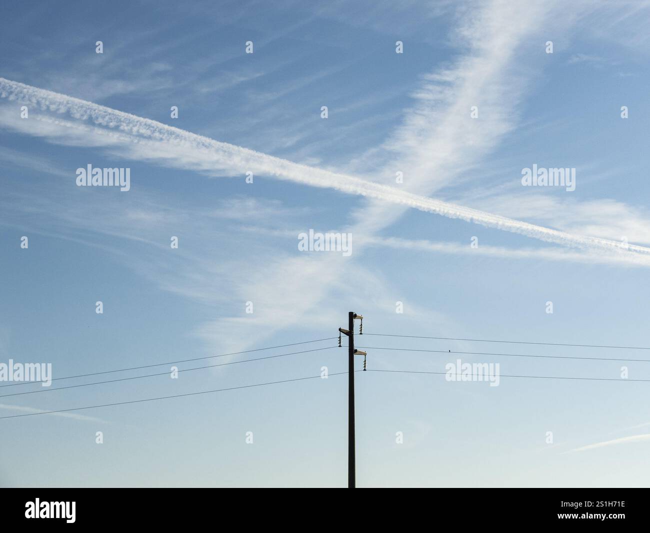 Electric wires supported by a pole and cloud streaks mixed with ...