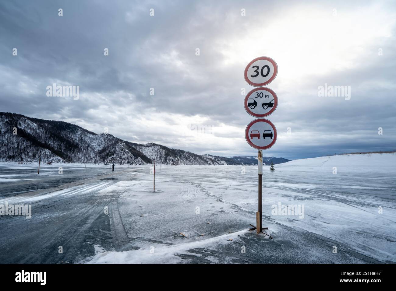 Traffic signs are displayed on a frozen road in snowy mountains ...