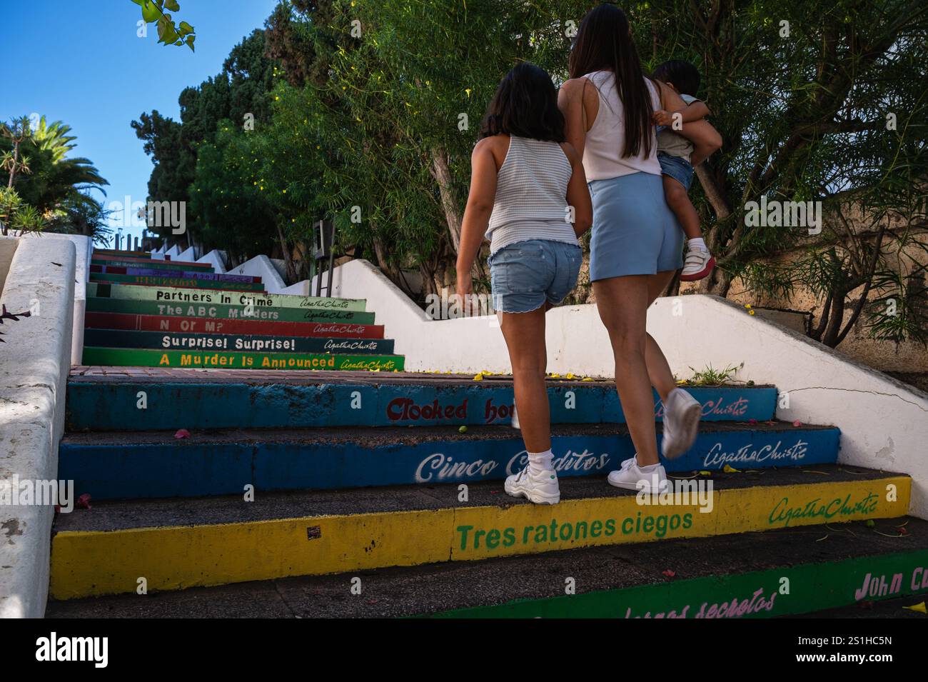 A group of people are walking up a set of stairs with colorful steps ...