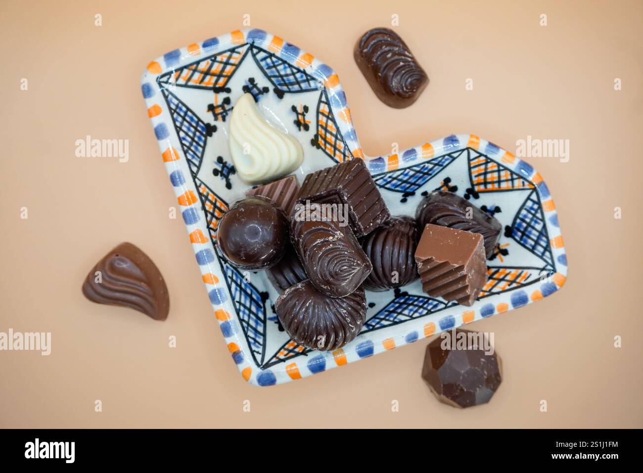 ceramic dish filled with various pieces of dark chocolate, each with ...