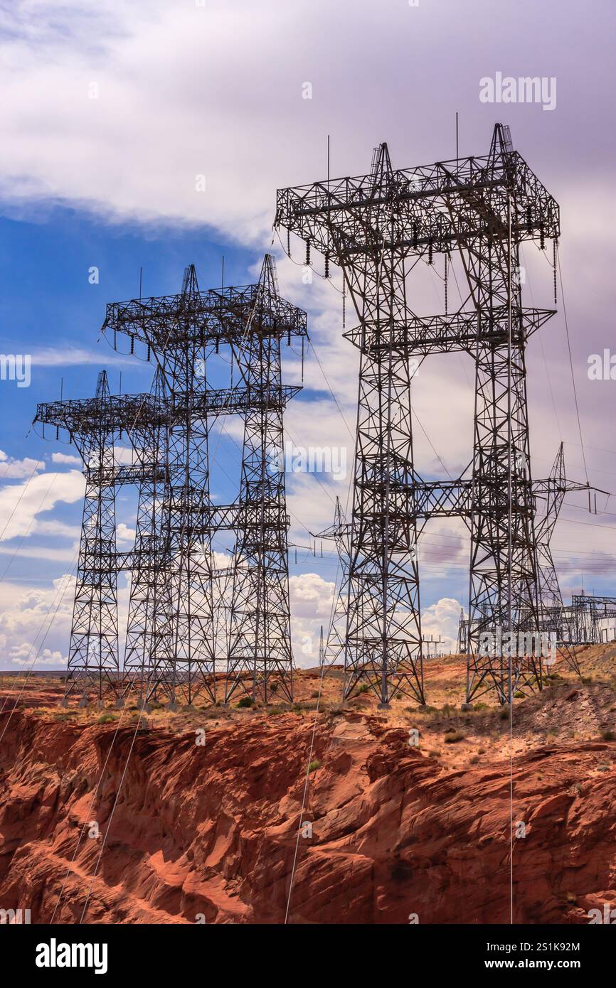 Three tall power lines are on a hillside. The sky is blue and there are ...