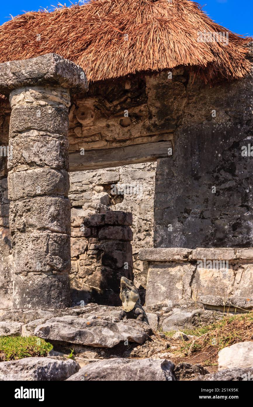 A small building with a thatched roof and a stone pillar. A small ...