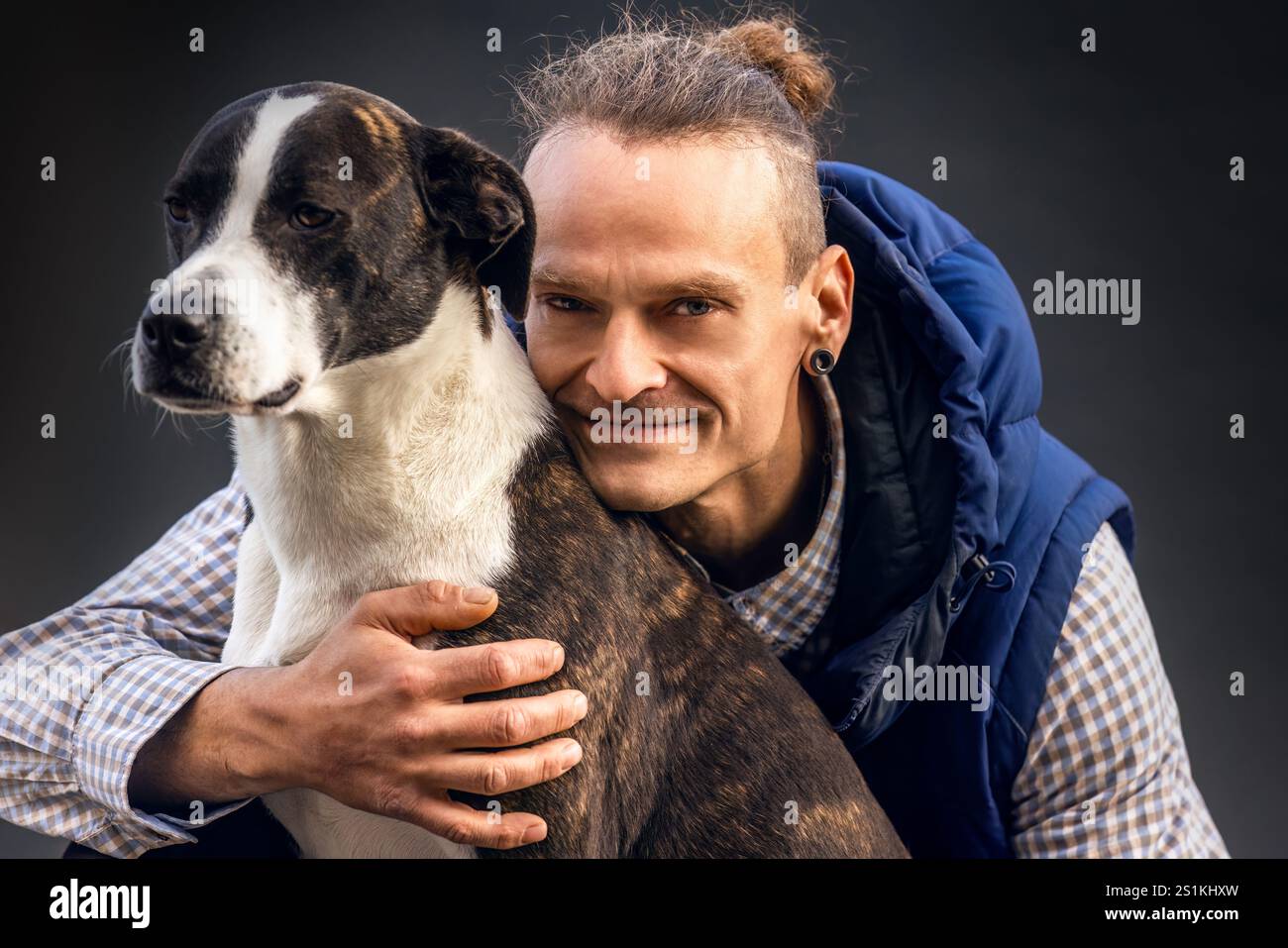 A man cuddle with his crossbreed dog in front of dark studio background Stock Photo - Alamy